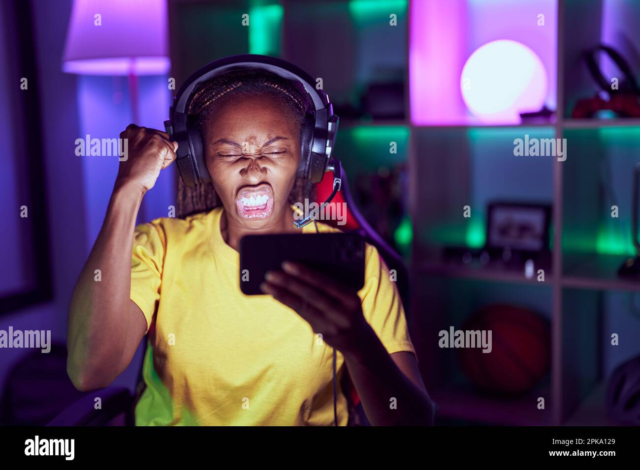 African american woman playing video games with smartphone annoyed and ...