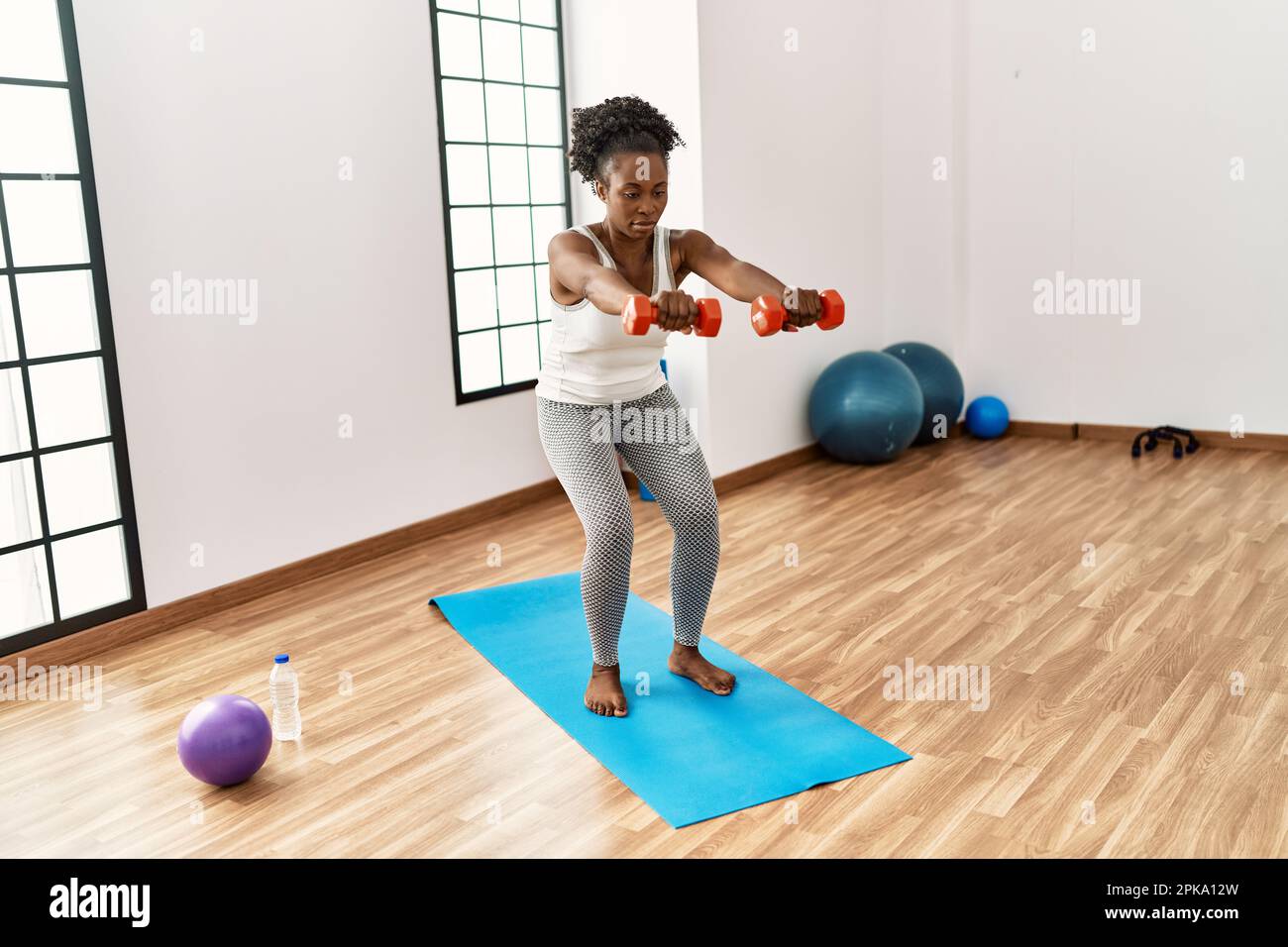 African american woman using dumbbells training at sport center Stock ...