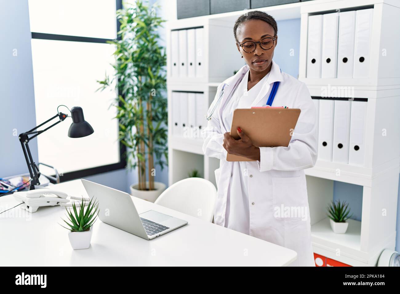 African american woman doctor smiling confident writing medical report ...