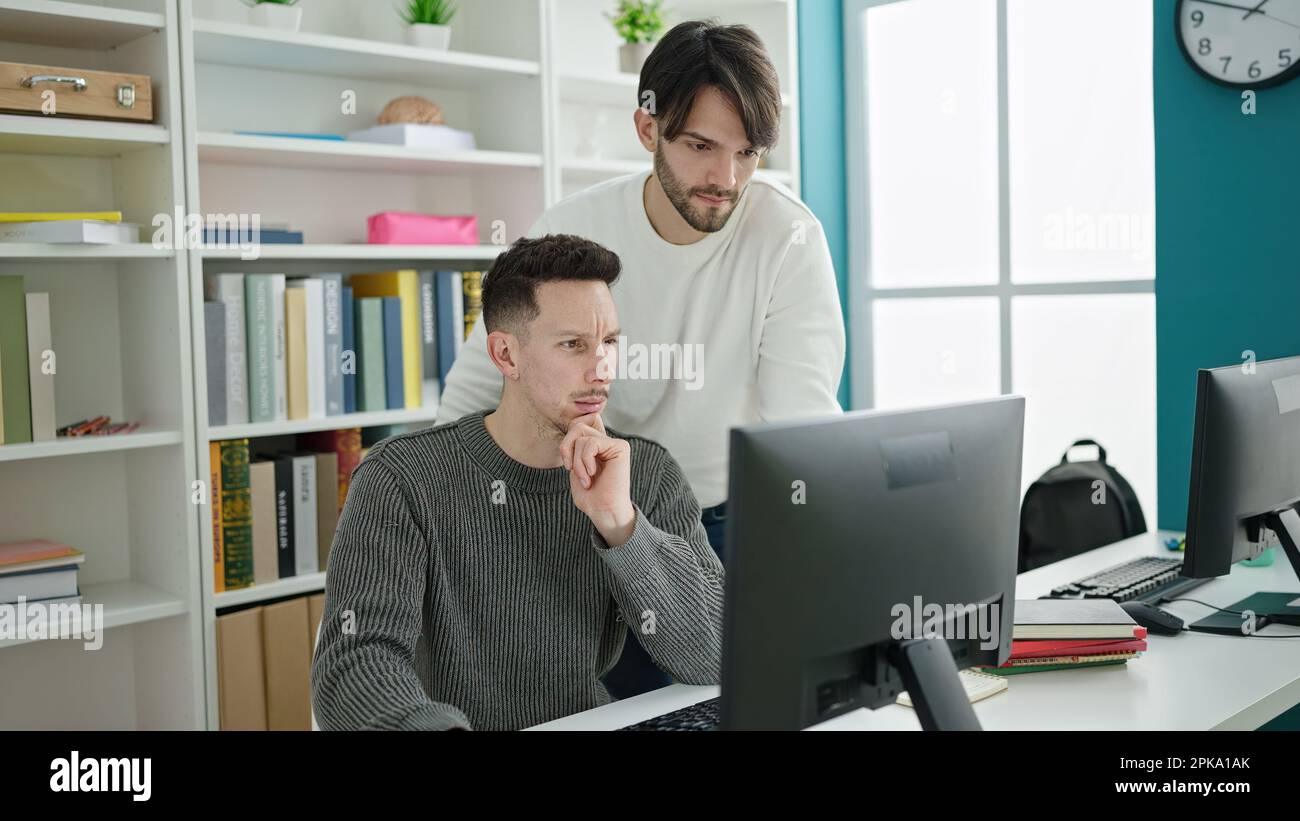 Two men students using computer studying at library university Stock Photo - Alamy
