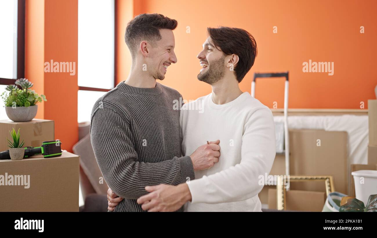 Two men couple hugging each other standing at new home Stock Photo - Alamy