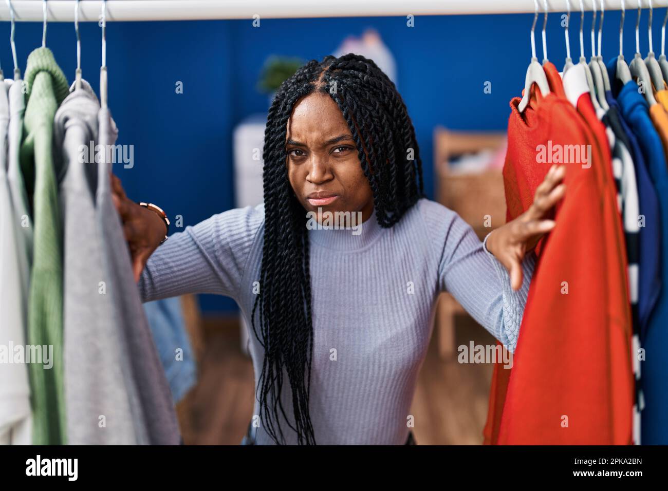 African american woman searching clothes on clothing rack clueless and ...