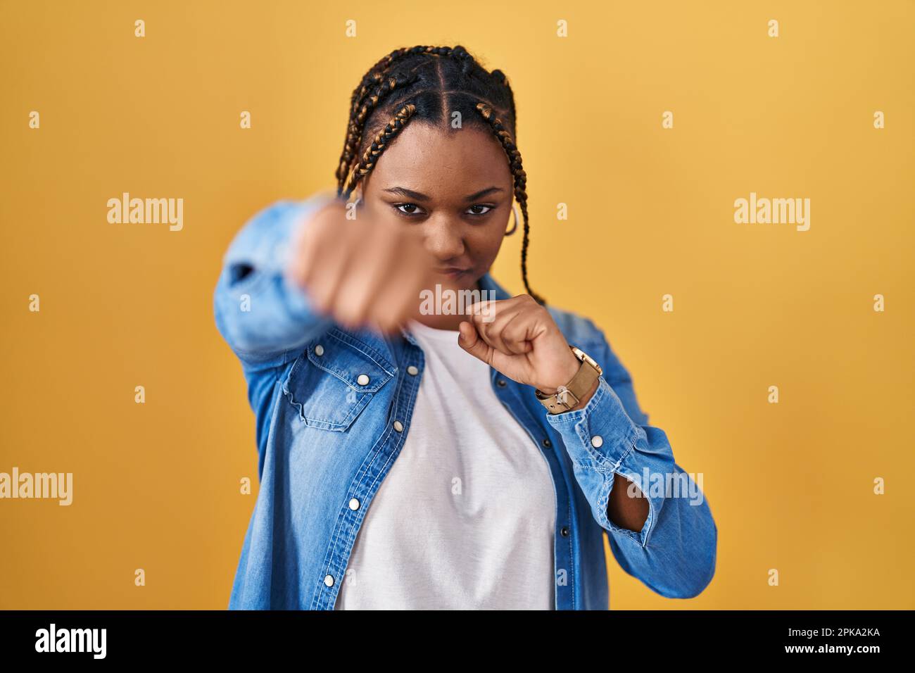 African american woman with braids standing over yellow background ...