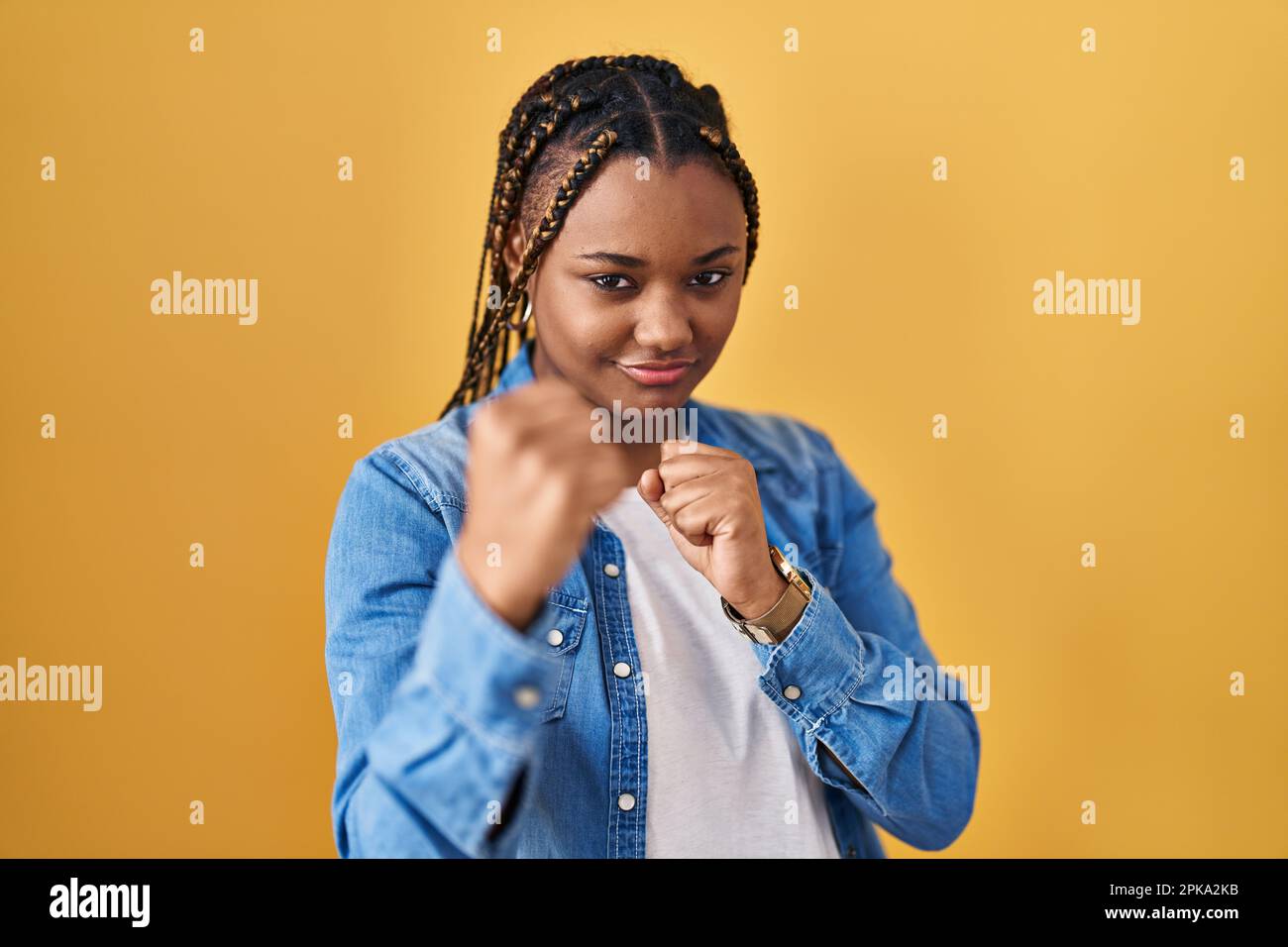 African american woman with braids standing over yellow background ...