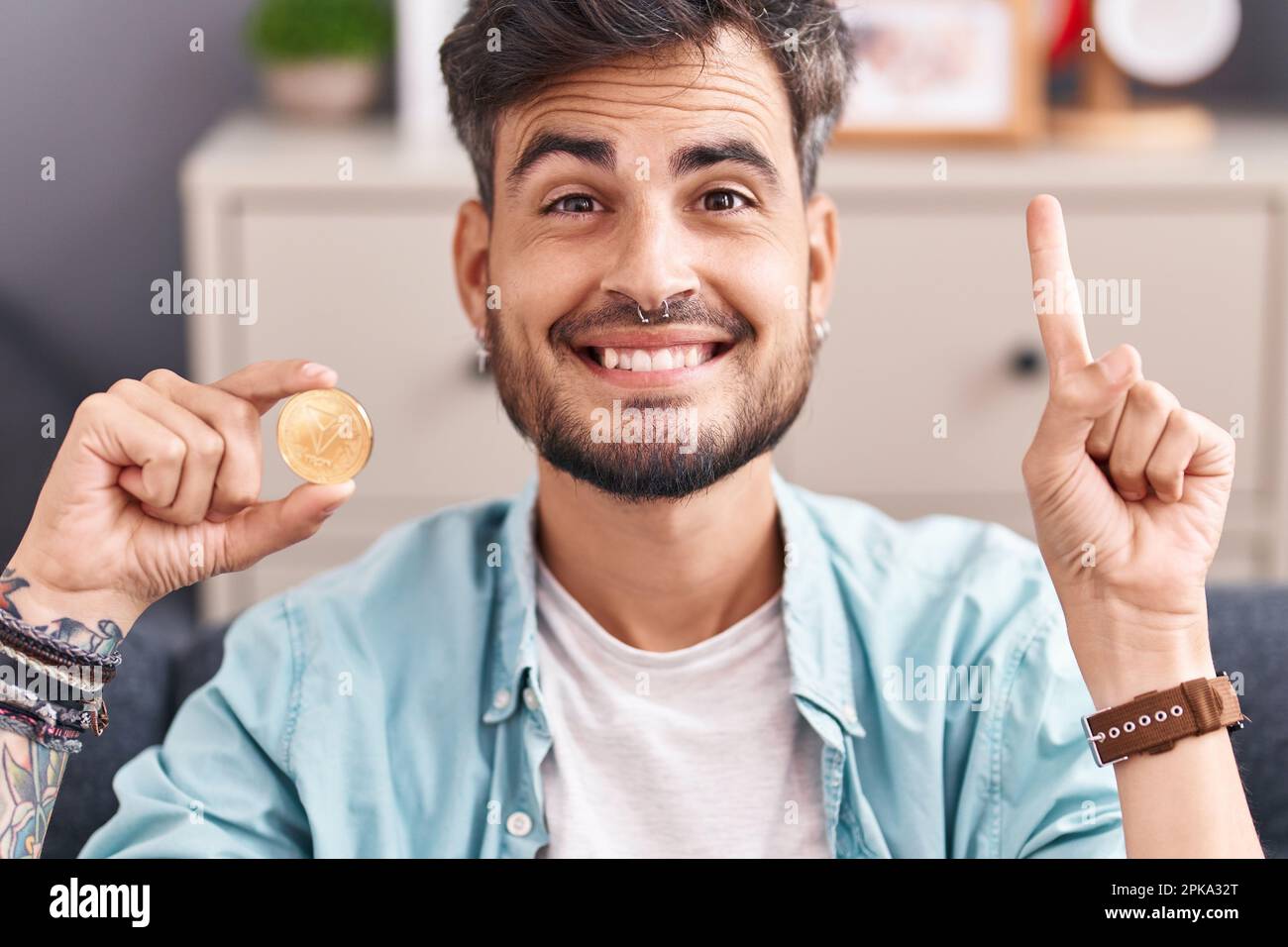 Young hispanic man with tattoos holding tron cryptocurrency coin ...