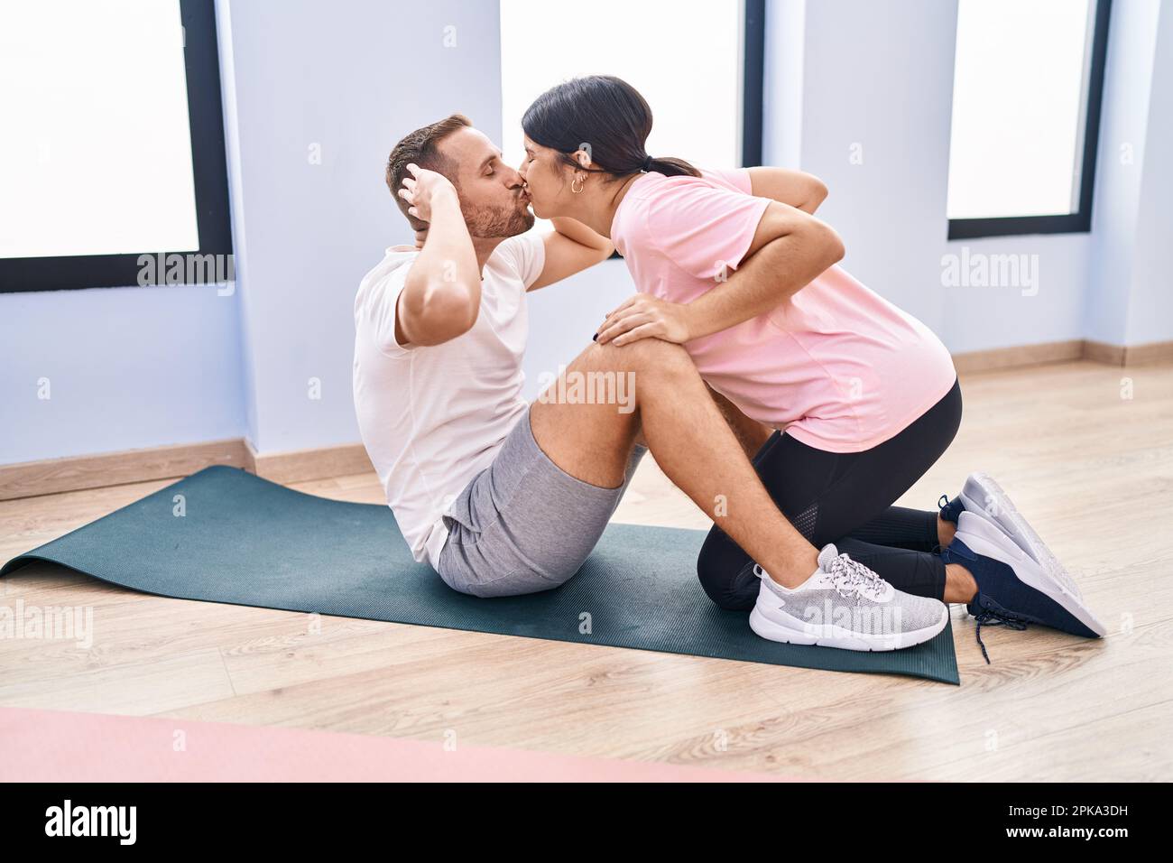 Man And Woman Couple Training Abs Exercise And Kissing At Sport Center