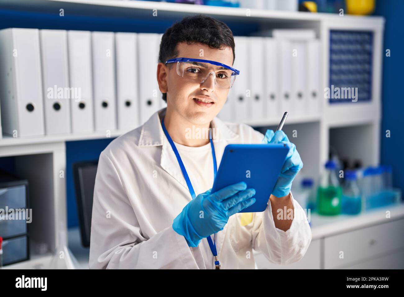 Young non binary man scientist smiling confident write on touchpad at laboratory Stock Photo - Alamy
