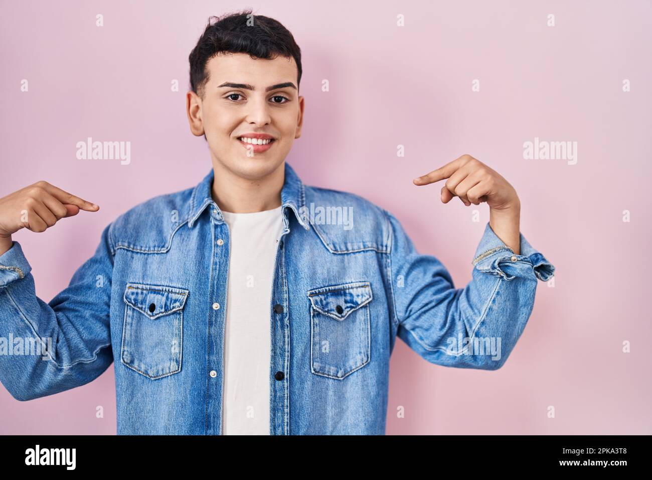Non binary person standing over pink background looking confident with ...