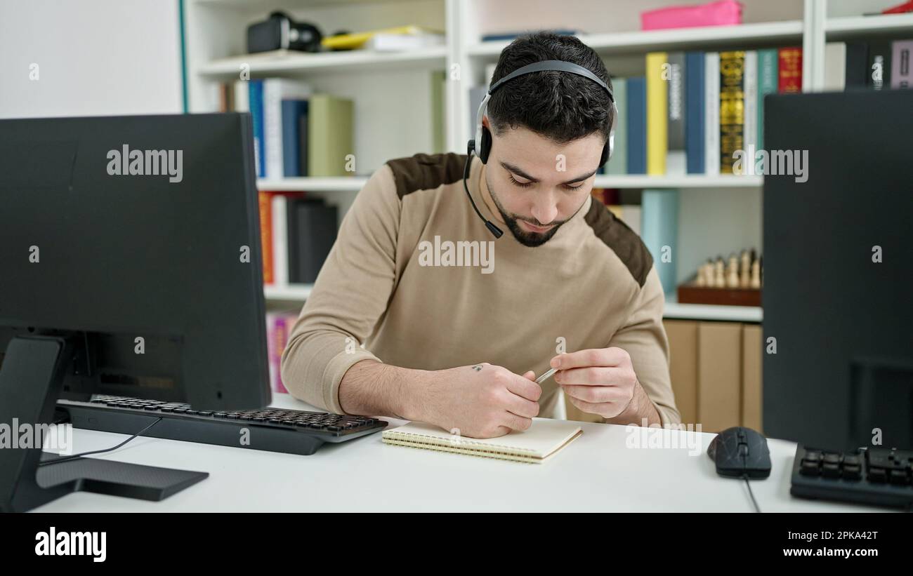 Young arab man student writing on notebook at university classroom ...