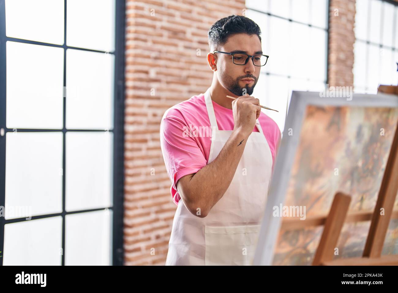 Young arab man artist looking draw with doubt expression at art studio ...