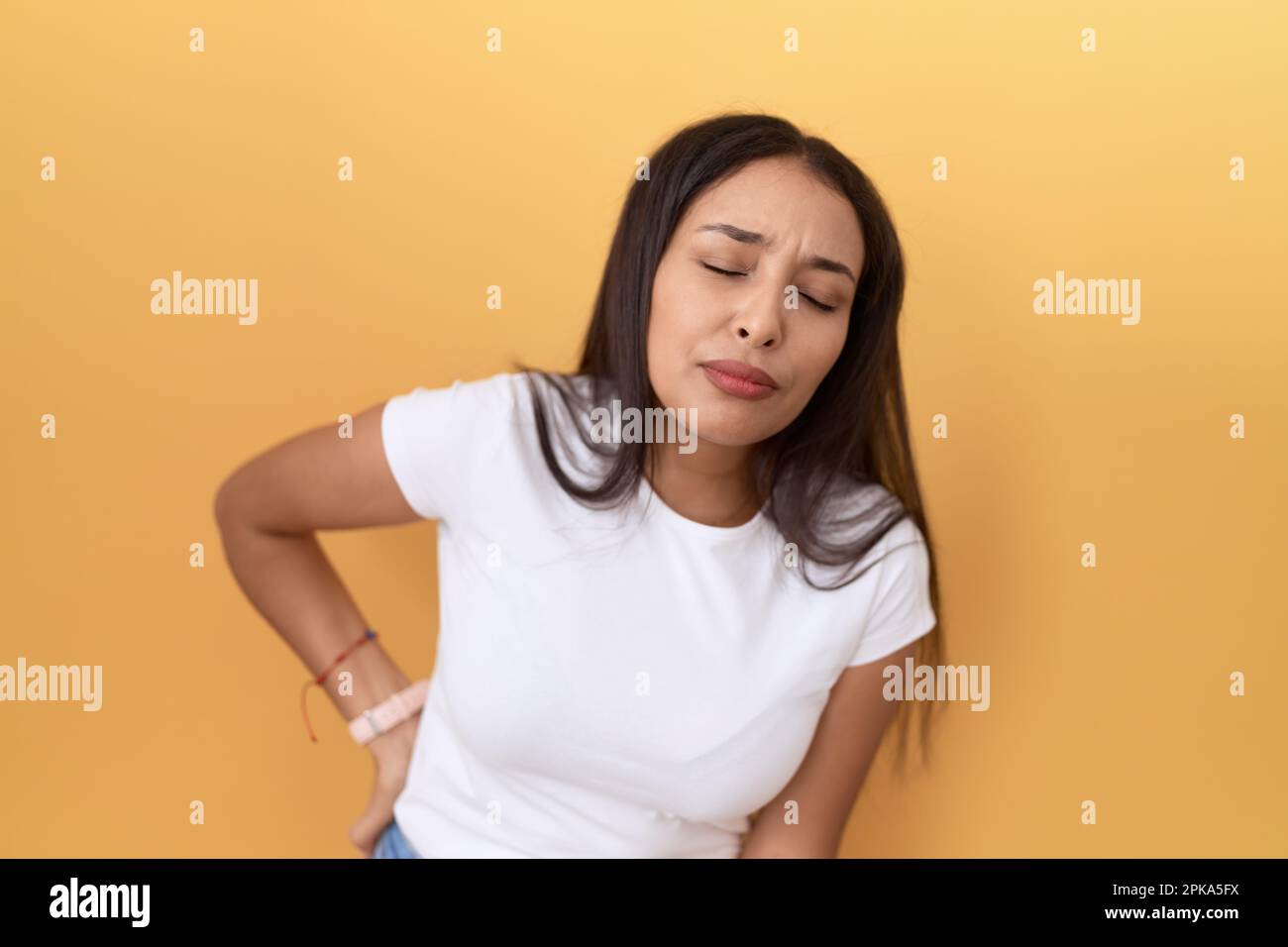 Young arab woman wearing casual white t shirt over yellow background ...