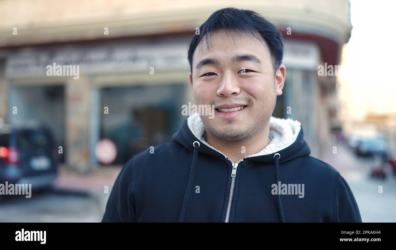 Young chinese man smiling confident standing at street Stock Photo - Alamy