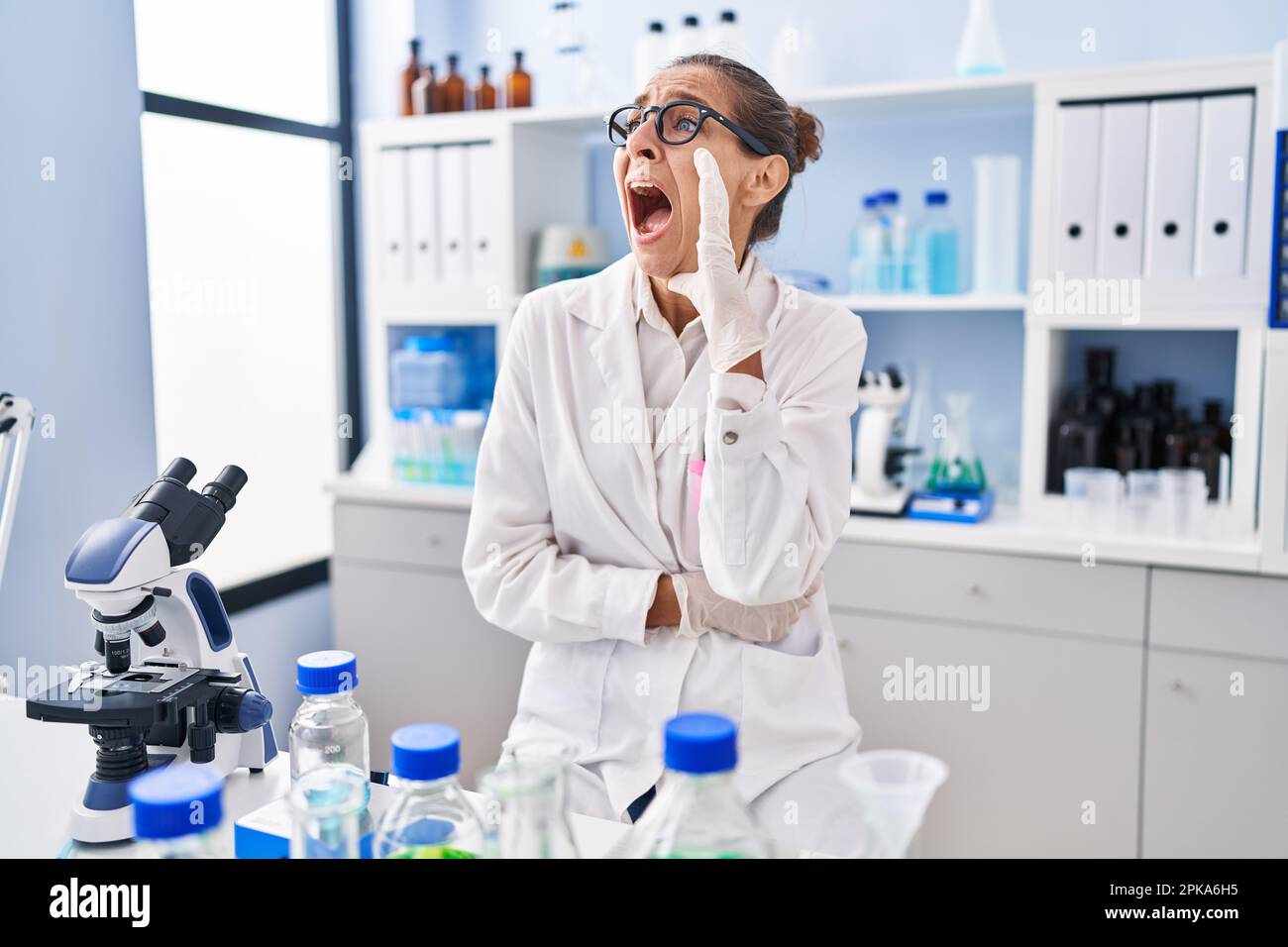 Young woman working at scientist laboratory clueless and confused with ...