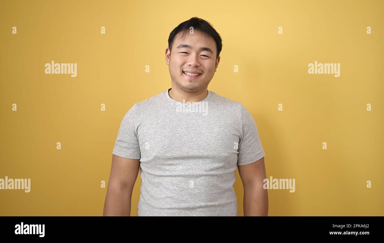 Young chinese man smiling confident standing over isolated yellow ...