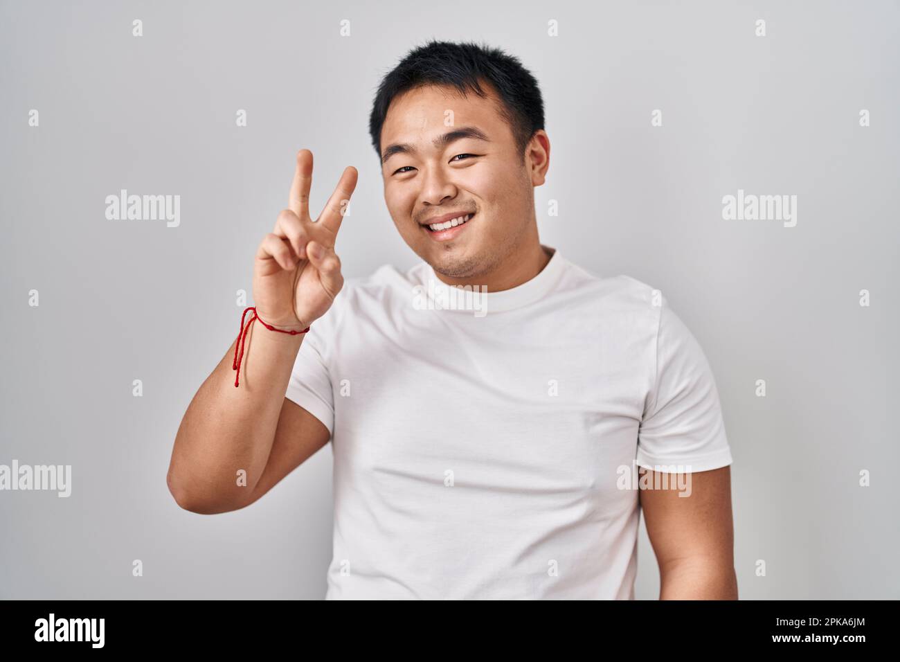 Young chinese man standing over white background smiling looking to the ...