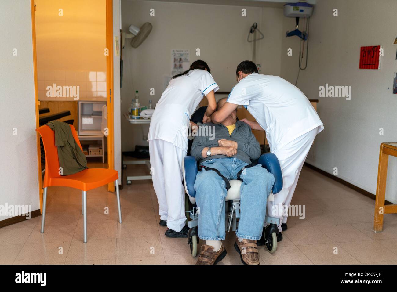 Two Nursing Assistants Put A Disabled Patient To Bed In Her Room At The
