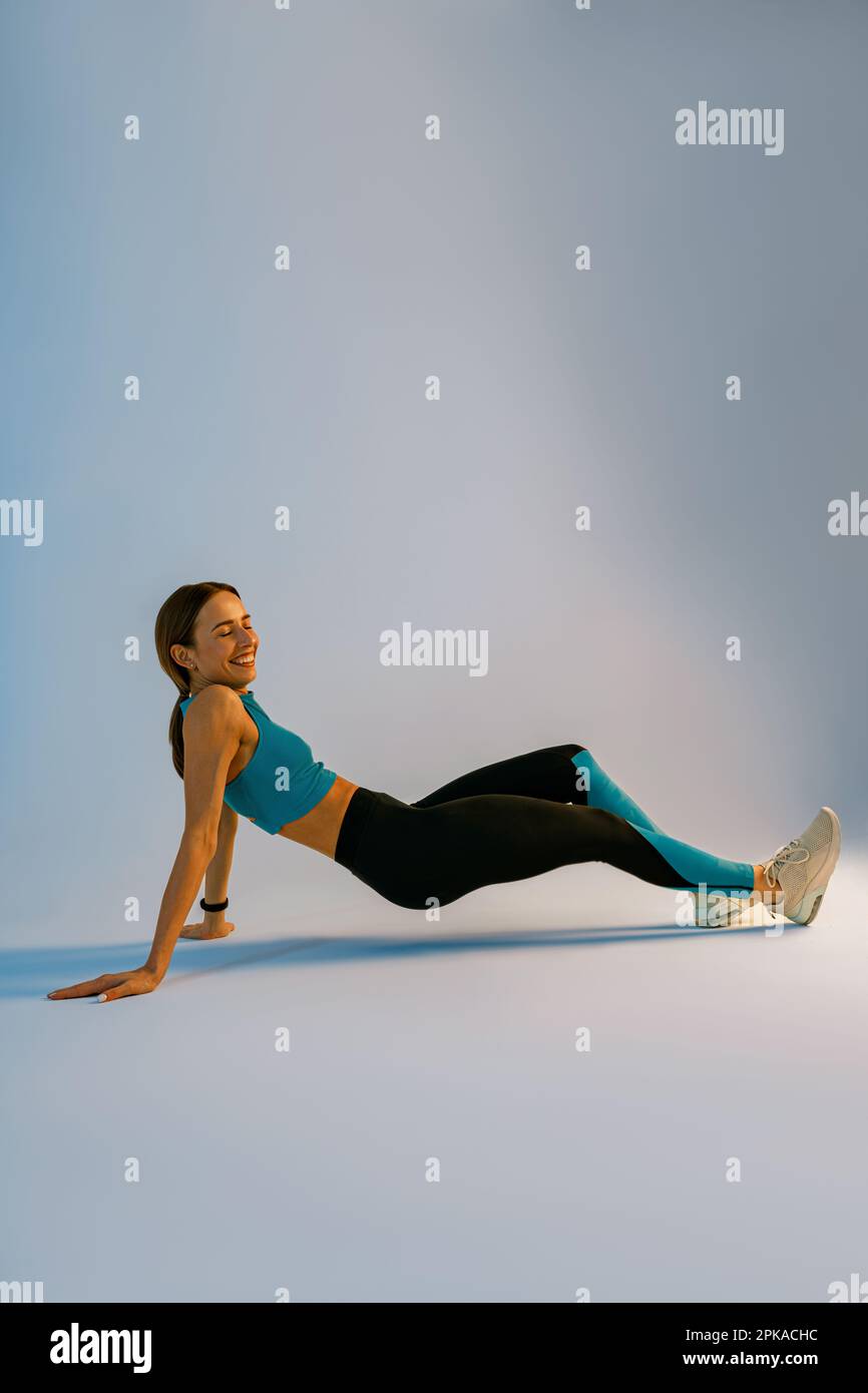 Smiling Fit Woman standing in plank position on studio background ...