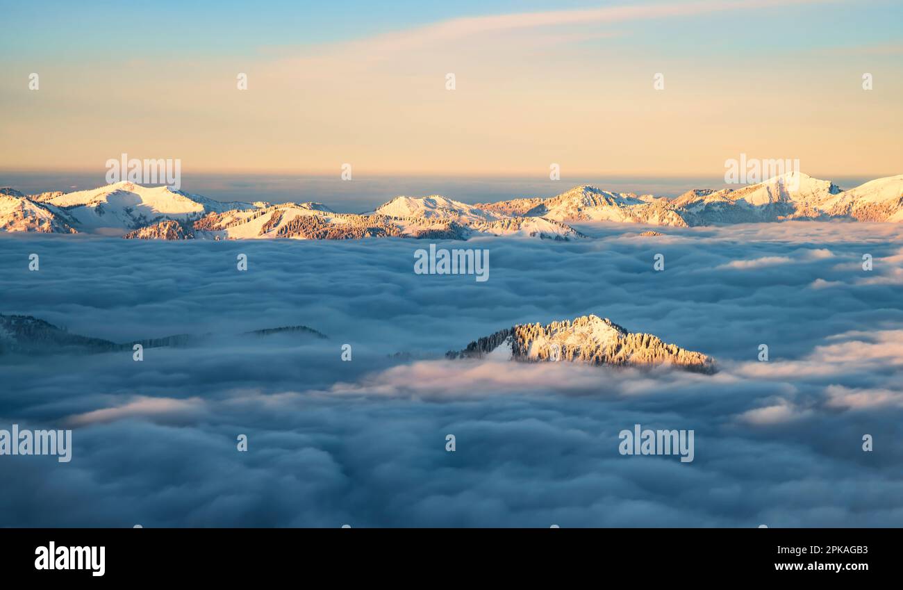 Snowy mountain landscape above cloud cover on a sunny winter morning ...