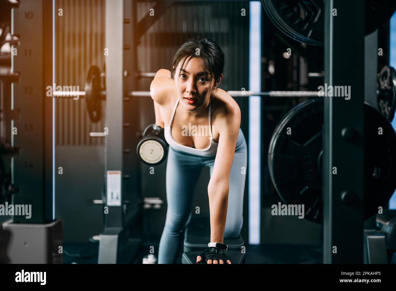 Strong woman taking weight lifting with dumbbells in sport club at gym ...