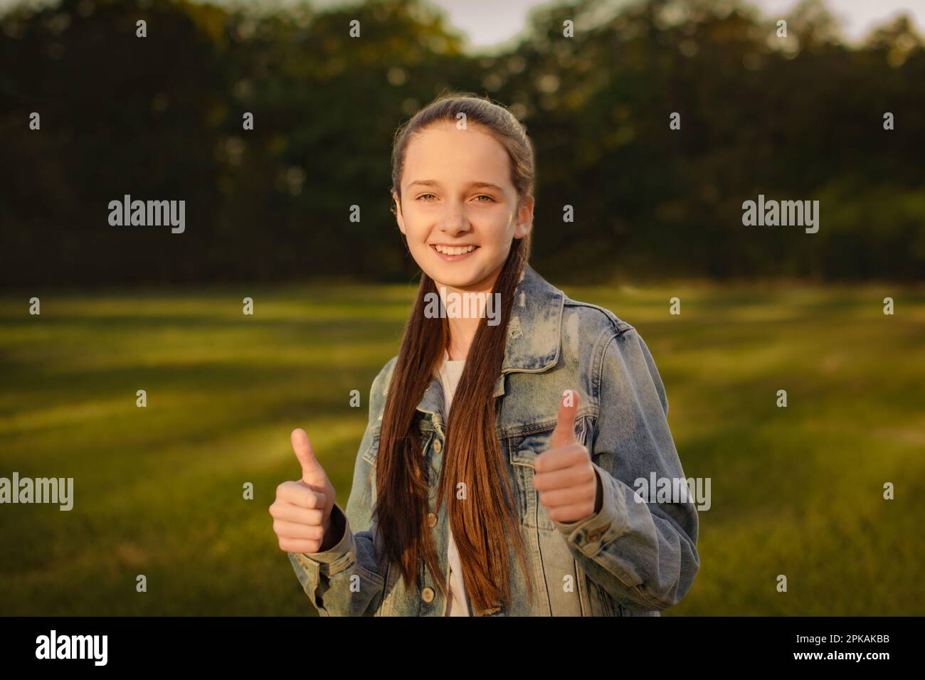 smiling happy teenager girl making thumbs up gesture both hands ...