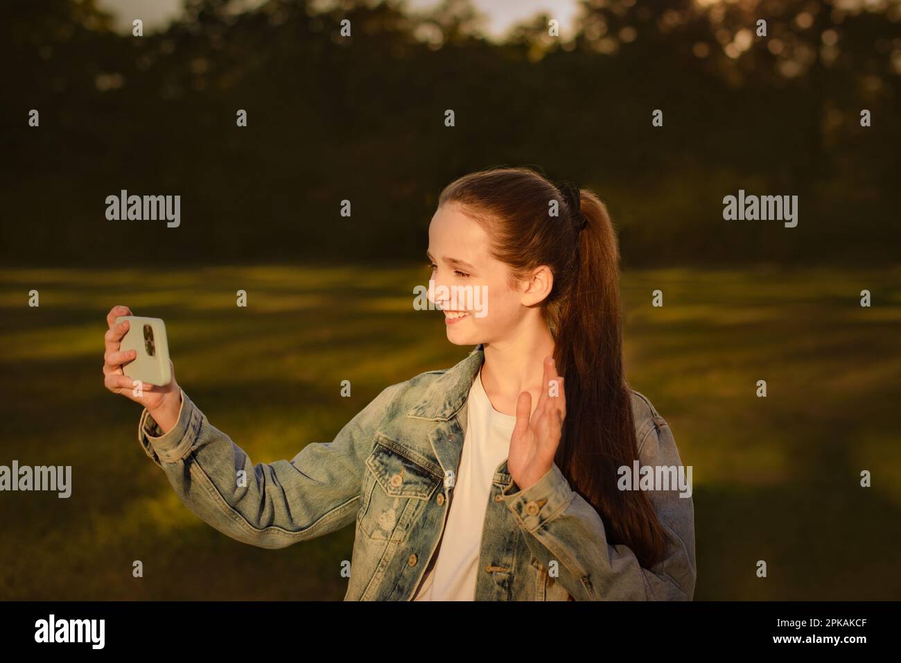 happy teenager girl greets and waves her hand at smartphone camera in ...