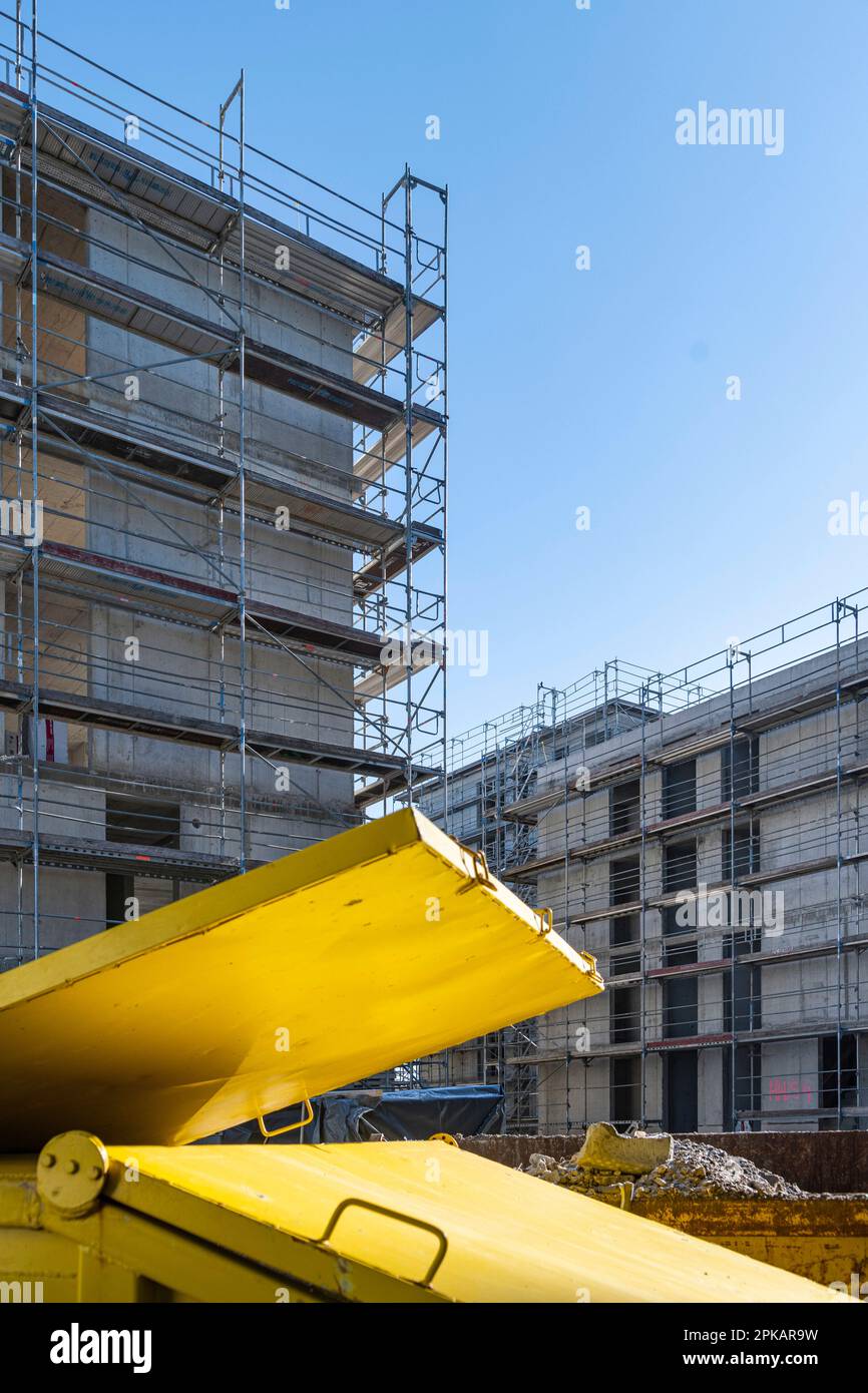 Yellow container for construction waste stands in front of scaffolded ...