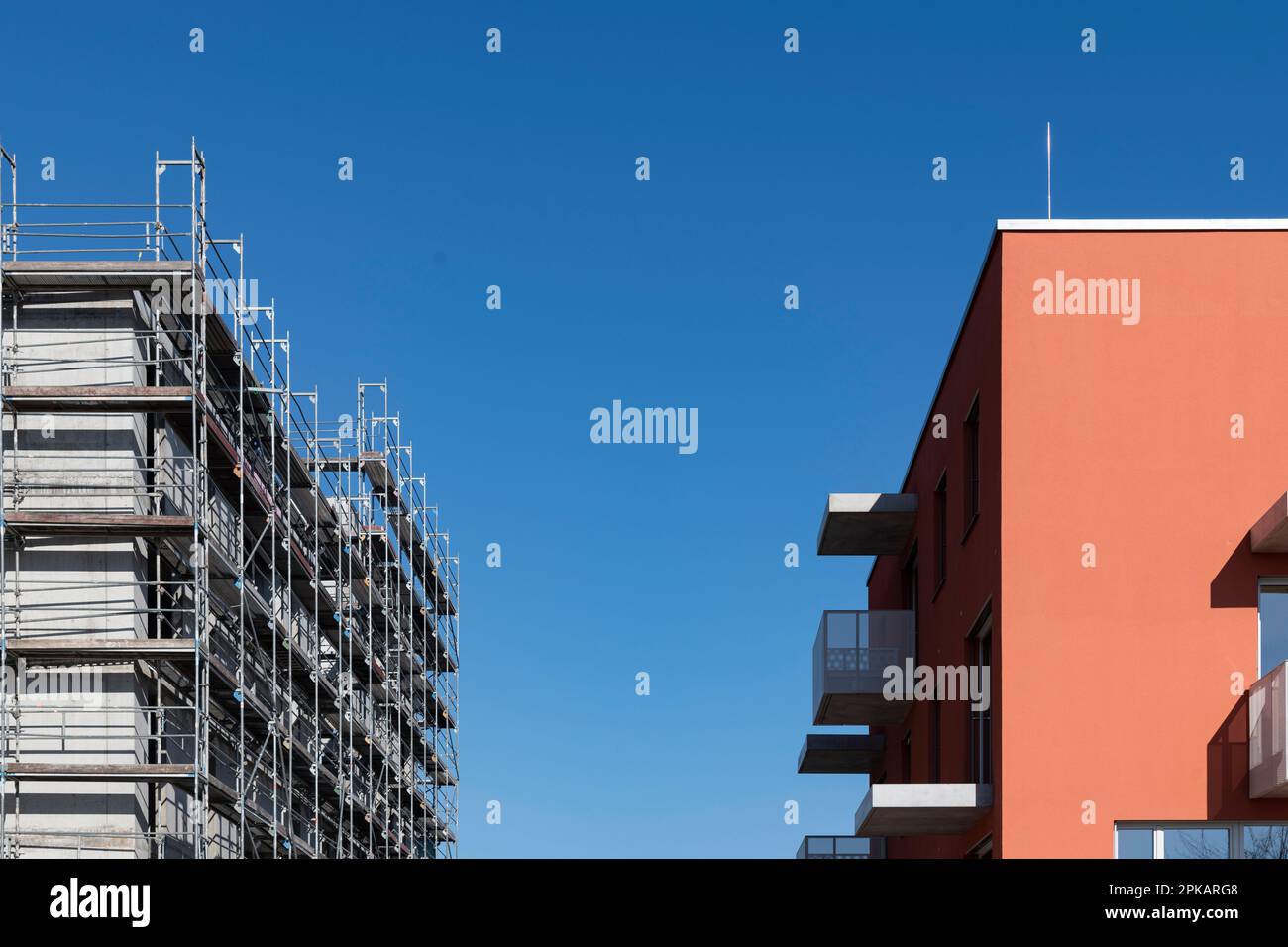 a finished new building faces a scaffolded building in shell against a ...