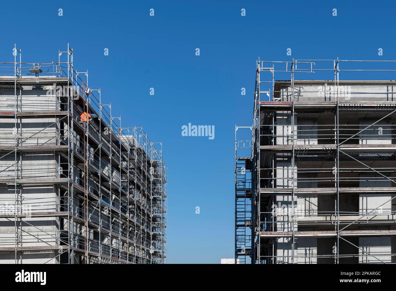 two scaffolded buildings in shell face each other in front of bright ...