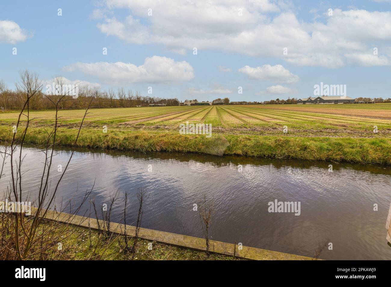 a small river in the middle of an open field with trees and grass on ...