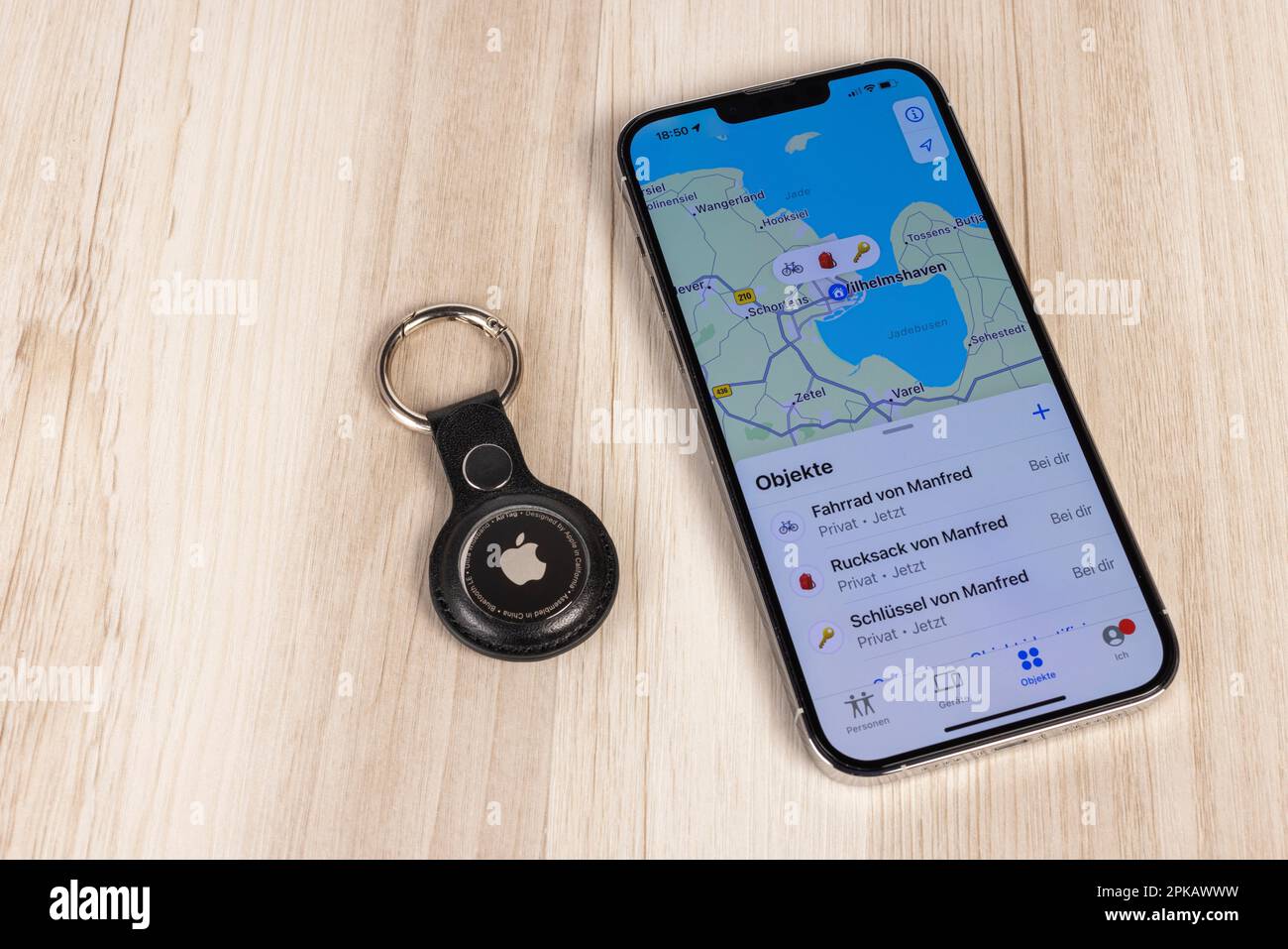 Black AirTag keychain lying next to iPhone, display, 'where is?' App ...