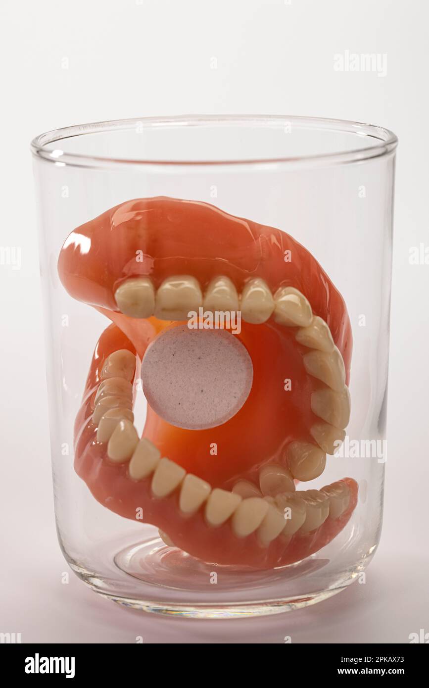 Denture with cleaning tablet in empty water glass, symbol image, clean ...