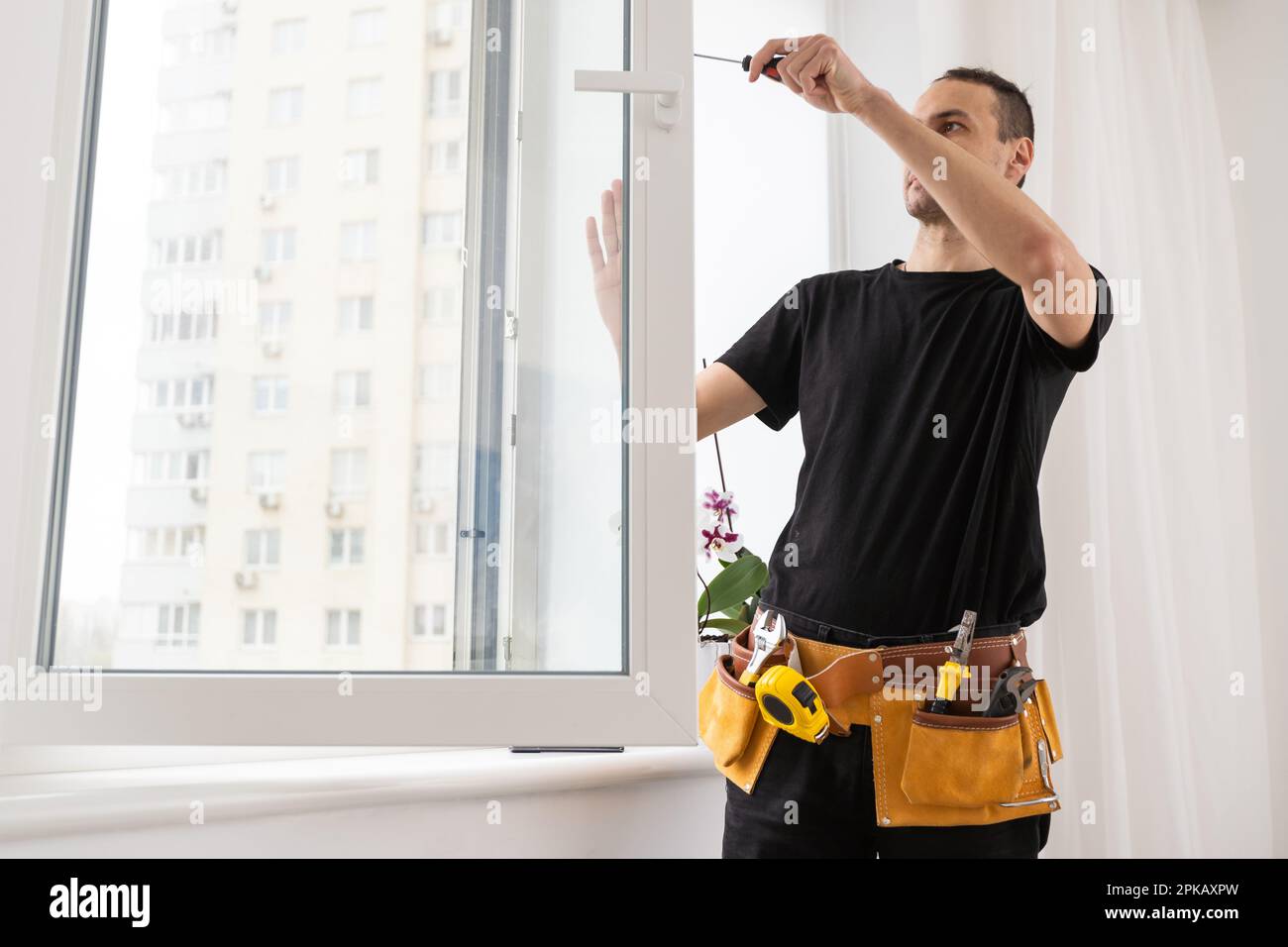 Handsome young man installing bay window in a new house construction ...