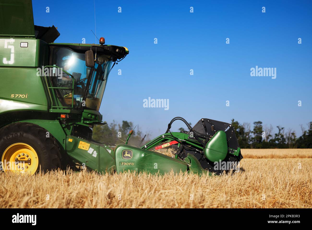 John Deere harvester works in the field. Combine Harvesting Wheat ...