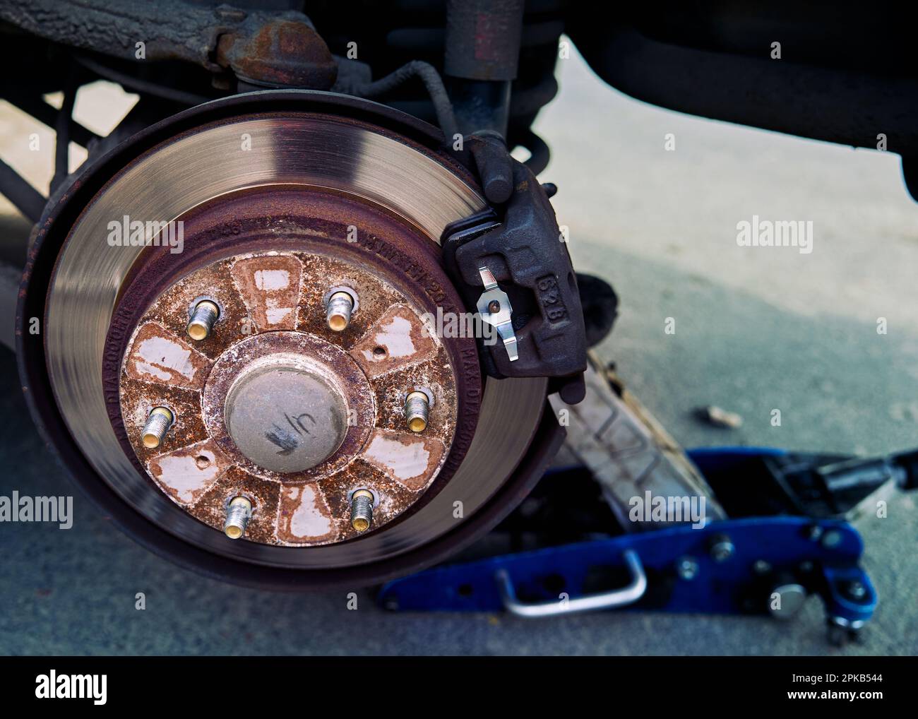 Car rusty brake rotor in automobile workshop front photo with jack ...