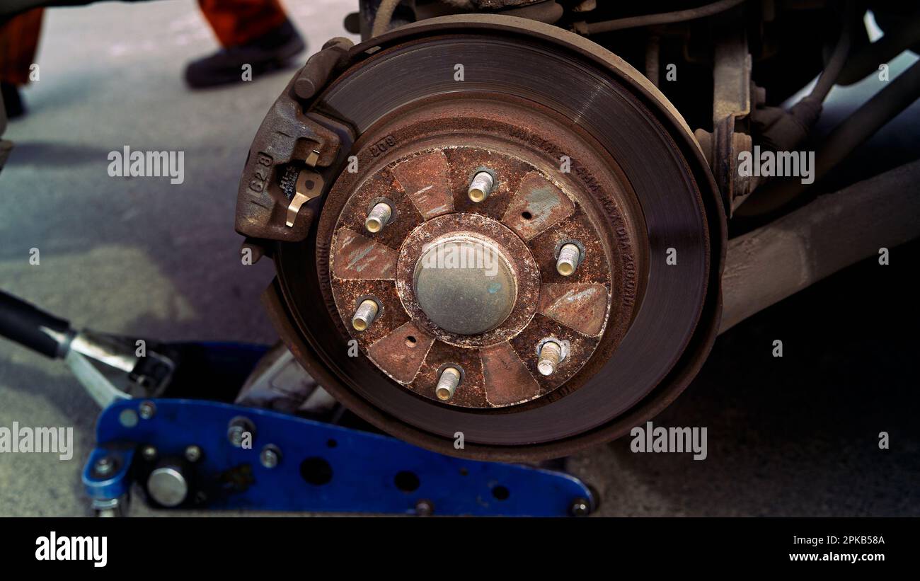 Car rusty brake rotor in automobile workshop front photo with jack ...