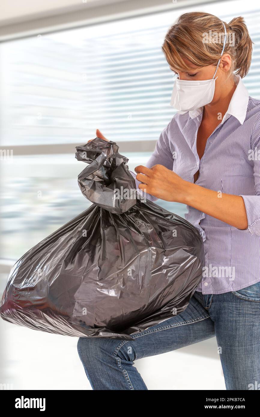 Young woman closing a garbage bag at home Stock Photo - Alamy