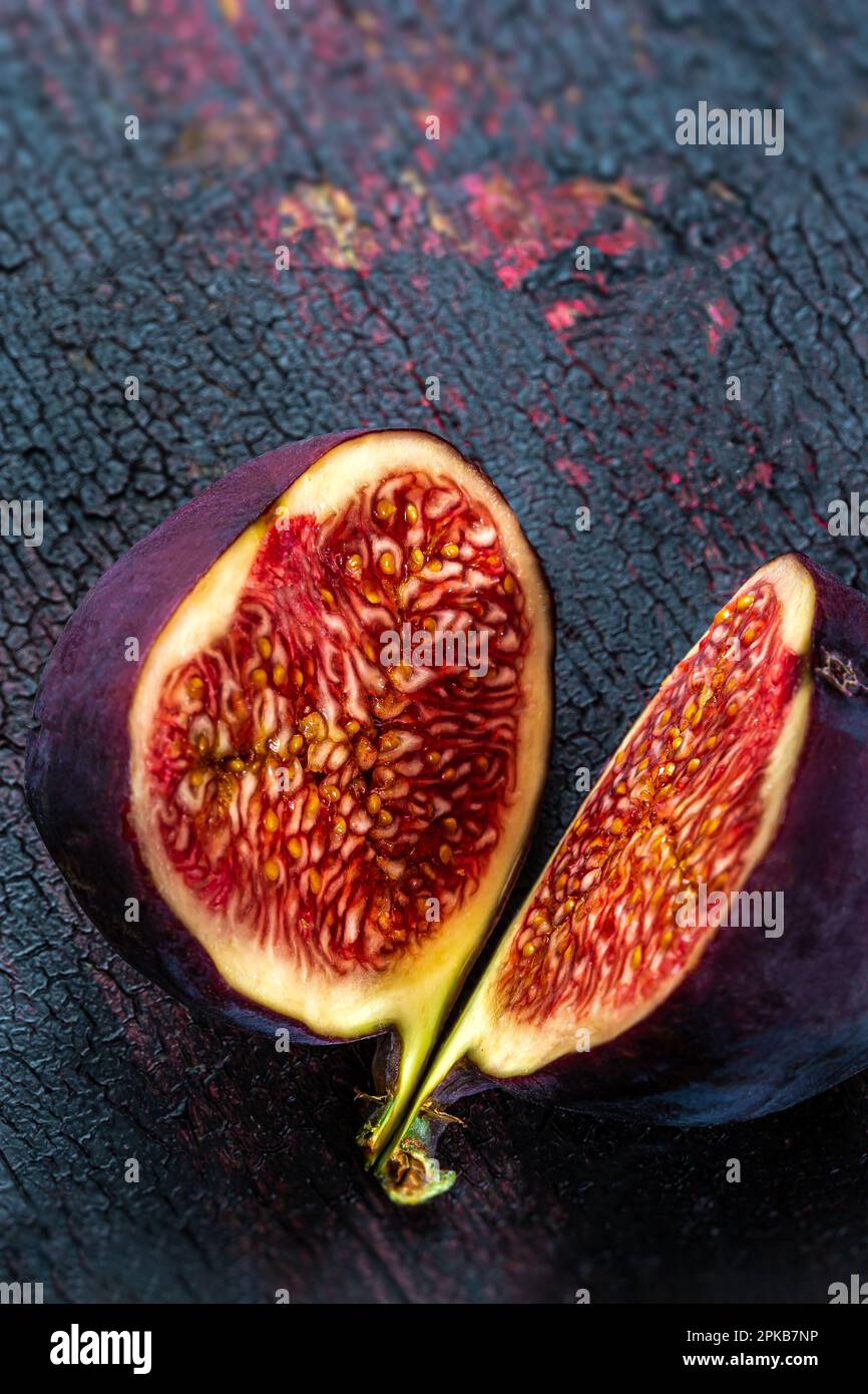 Black fig sliced in half close-up ready to eat top view on tone-on-tone ...