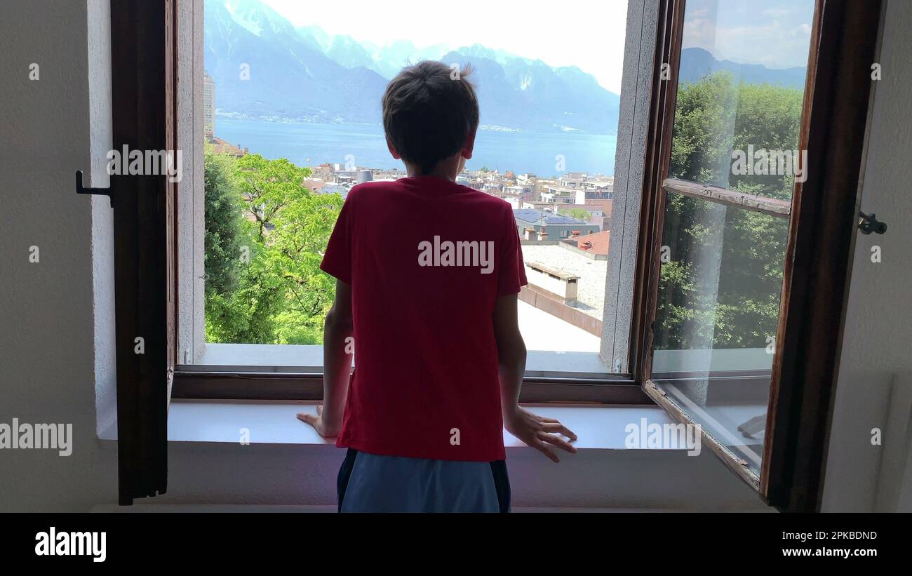 Young boy opening window looking outside. Child opens home windows ...