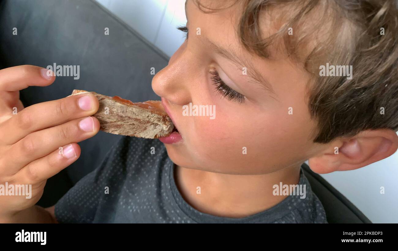 Young boy eating toast with jelly in morning breakfast. boy eats jelly ...