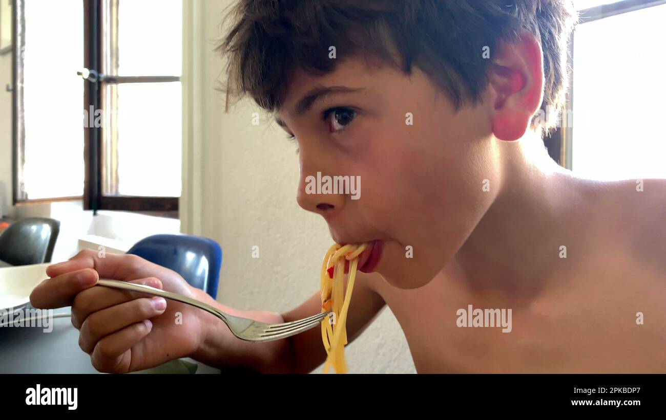 Young boy eating pasta. Child eats spaghetti Stock Photo - Alamy