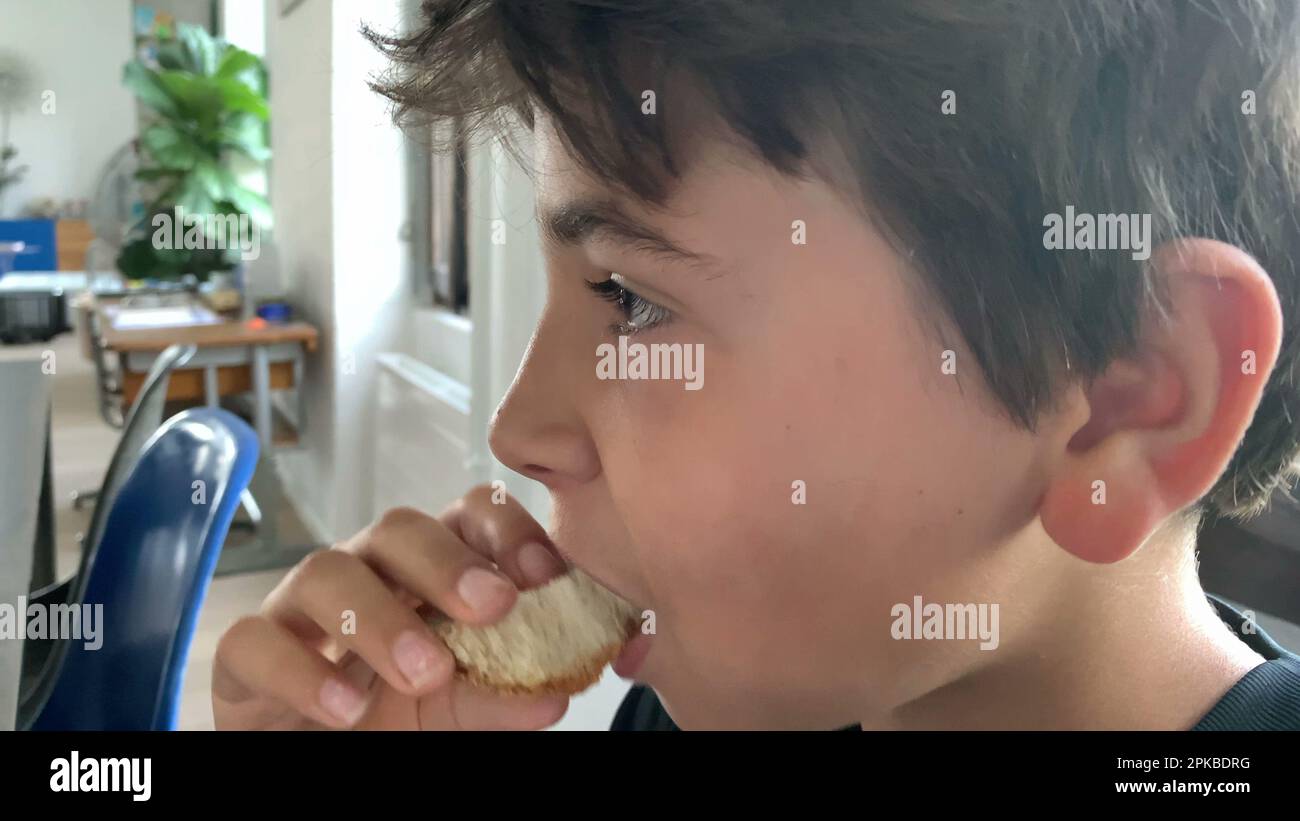 Young boy eating bread, child eats carb food chewing Stock Photo - Alamy