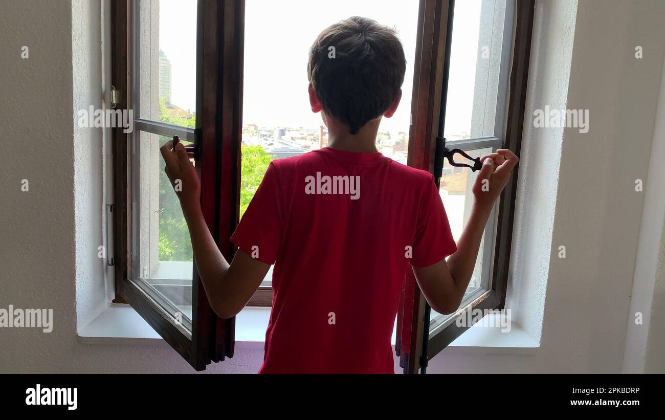 Young boy opening window looking outside. Child opens home windows ...