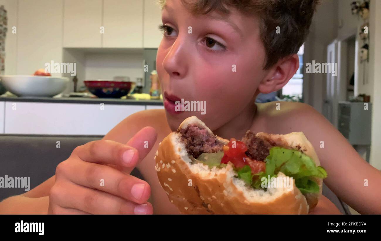 Young boy eating burger. Child taking a bite of hamburger Stock Photo ...