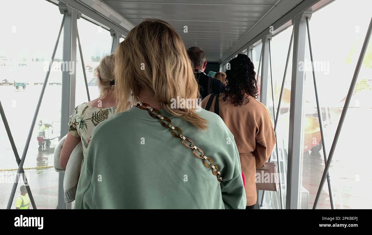 Passengers boarding plane at bridge. Crowd people standing waiting to ...