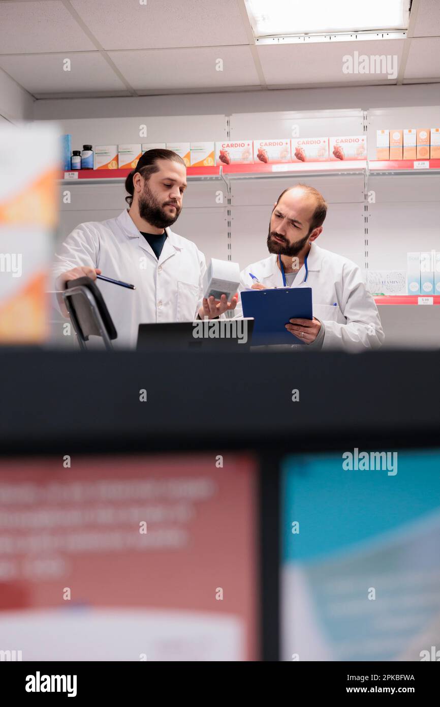 Caucasian colleagues standing at drugstore counter desk doing ...