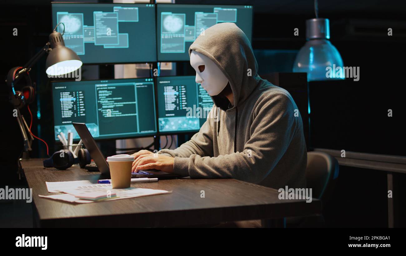 Cyber scammer wearing mask and hood to hack computer system, breaking ...