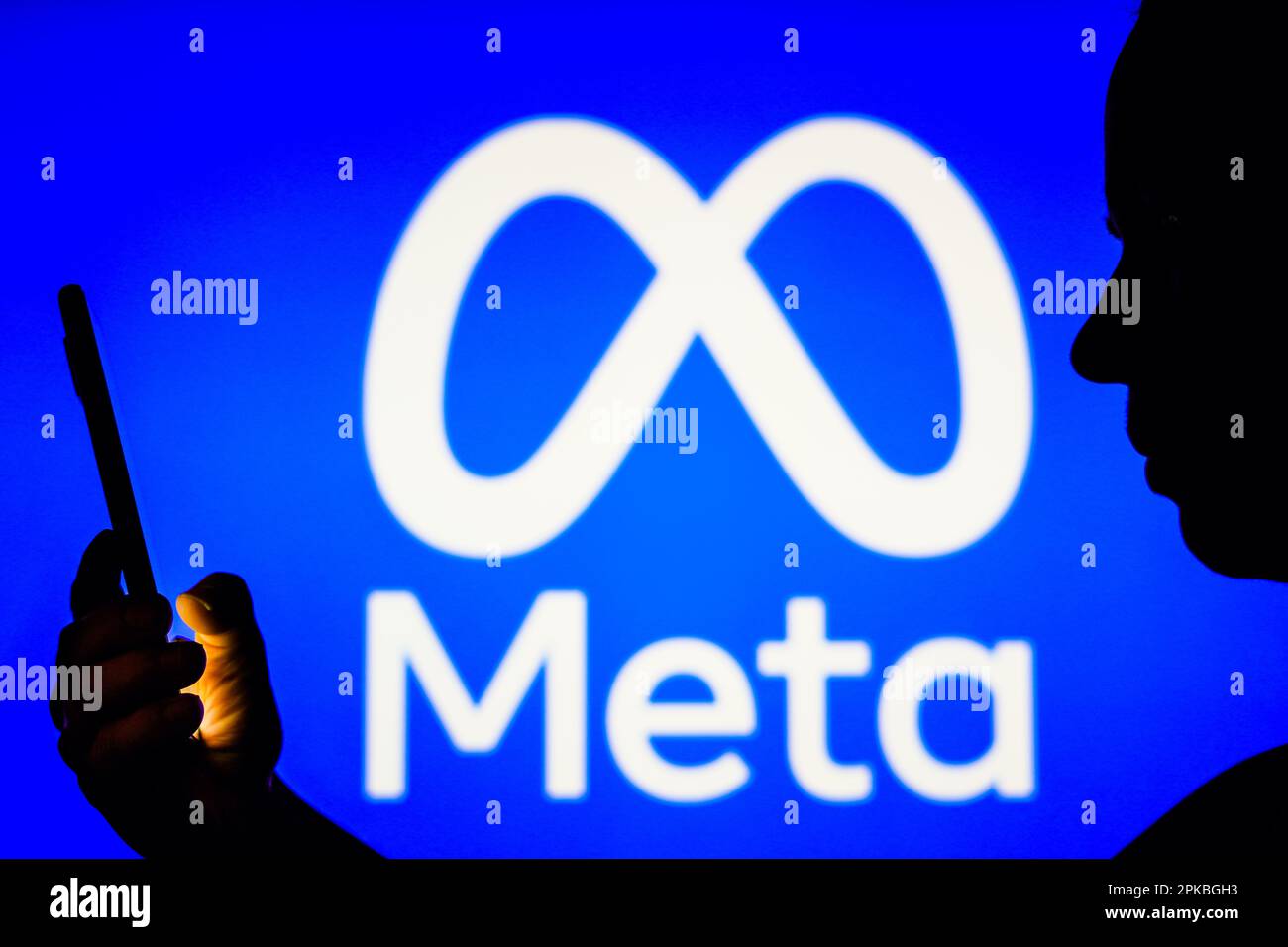 In this photo illustration, a woman's silhouette holds a smartphone with the Meta Platforms, Inc ...