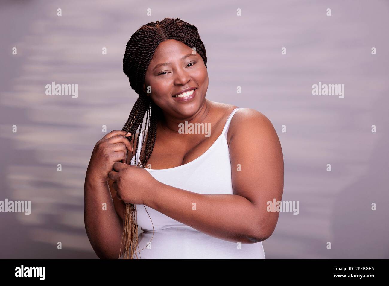 Body positive woman braiding long brown hair with ombre effect. Pretty ...