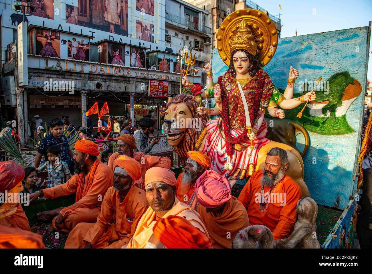 A group of sadhus in saffron attire sit around an embellished idol of ...