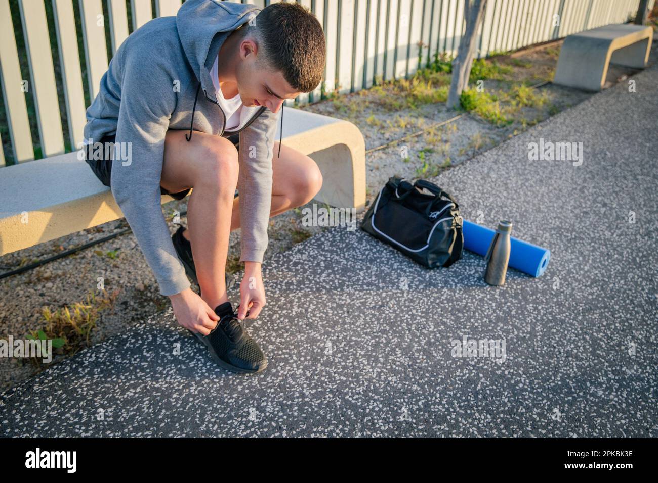 A sportsman sitting on a bench is tying his shoes, photo with copy ...